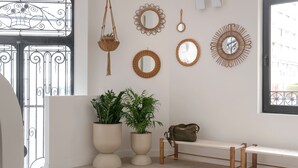 Quarto com um banco branco, duas plantas em vasos e diversos espelhos fixados na parede.