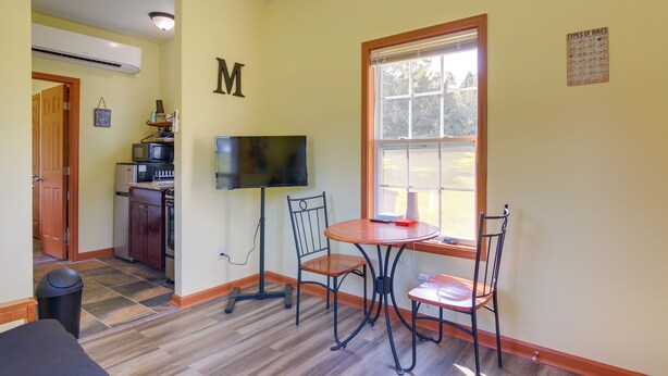 Quarto com uma mesa de jantar, duas cadeiras, televisão e janela com vista.