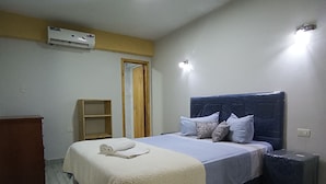 Quarto de hotel com cama, mesa de cabeceira e um aparelho de ar condicionado na parede.
