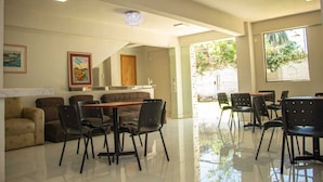 Amplo espaço interno com área de refeições, sofás e balcão de recepção.