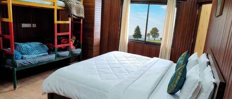 Quarto com beliche, cama de solteiro, ventilador de teto e janela com vista para árvores.