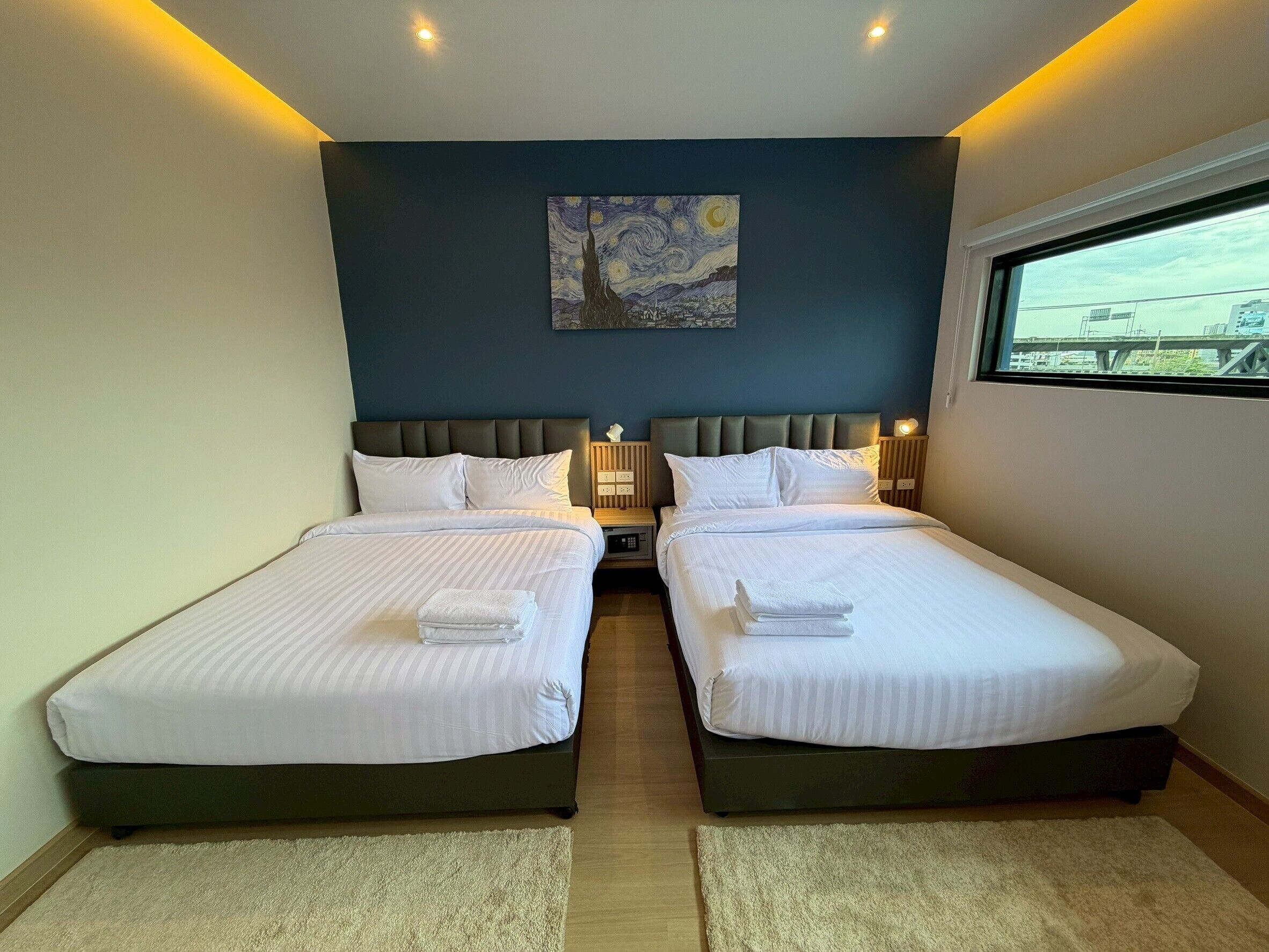Quarto de hotel com duas camas, um quadro na parede e janela com vista.