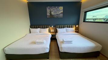 Quarto de hotel com duas camas, um quadro na parede e janela com vista.