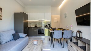 Uma cozinha moderna com armários cinzas, forno embutido e área de jantar com mesa e cadeiras.