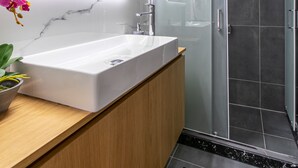 Uma casa de banho moderna com uma grande lavatório branca, um espelho e cabine de duche.