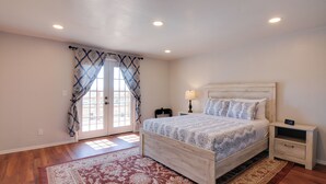 Quarto com cama de madeira, mesa de cabeceira com abajur e relógio.