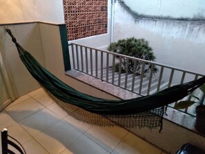 Uma rede numa varanda com vista para a rua abaixo.