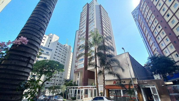 Um edifício alto com vários andares, cercado por outros edifícios altos.