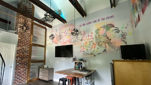 Uma cozinha moderna com parede de destaque em tijolo, vigas de madeira, uma televisão grande e um mural na parede.