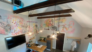 Uma cozinha com vigas de madeira, uma televisão e um mural com notas musicais.