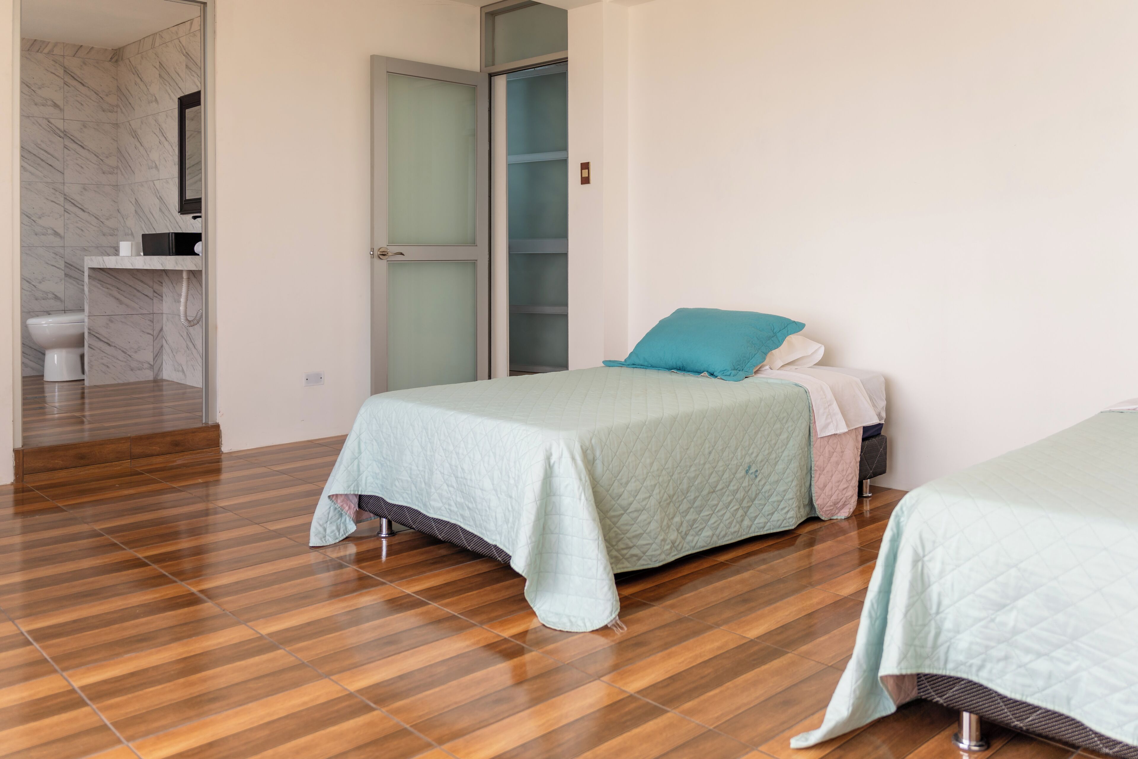 Quarto com duas camas, banheiro e armário.