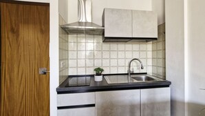 Cozinha moderna com cuba de aço inoxidável, fogão embutido e painel de azulejos brancos.