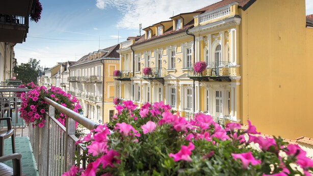 Uma fileira de edifícios amarelos com varandas, algumas com flores.