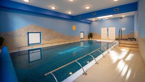 Uma piscina com água azul cristalina, rodeada por um chão bege e paredes com detalhes em azul.