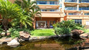 Um hotel com piscina, palmeiras e um jardim bem cuidado.