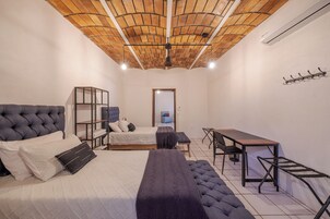 Quarto com uma cama grande, uma escrivaninha, uma cadeira e um guarda-roupa.