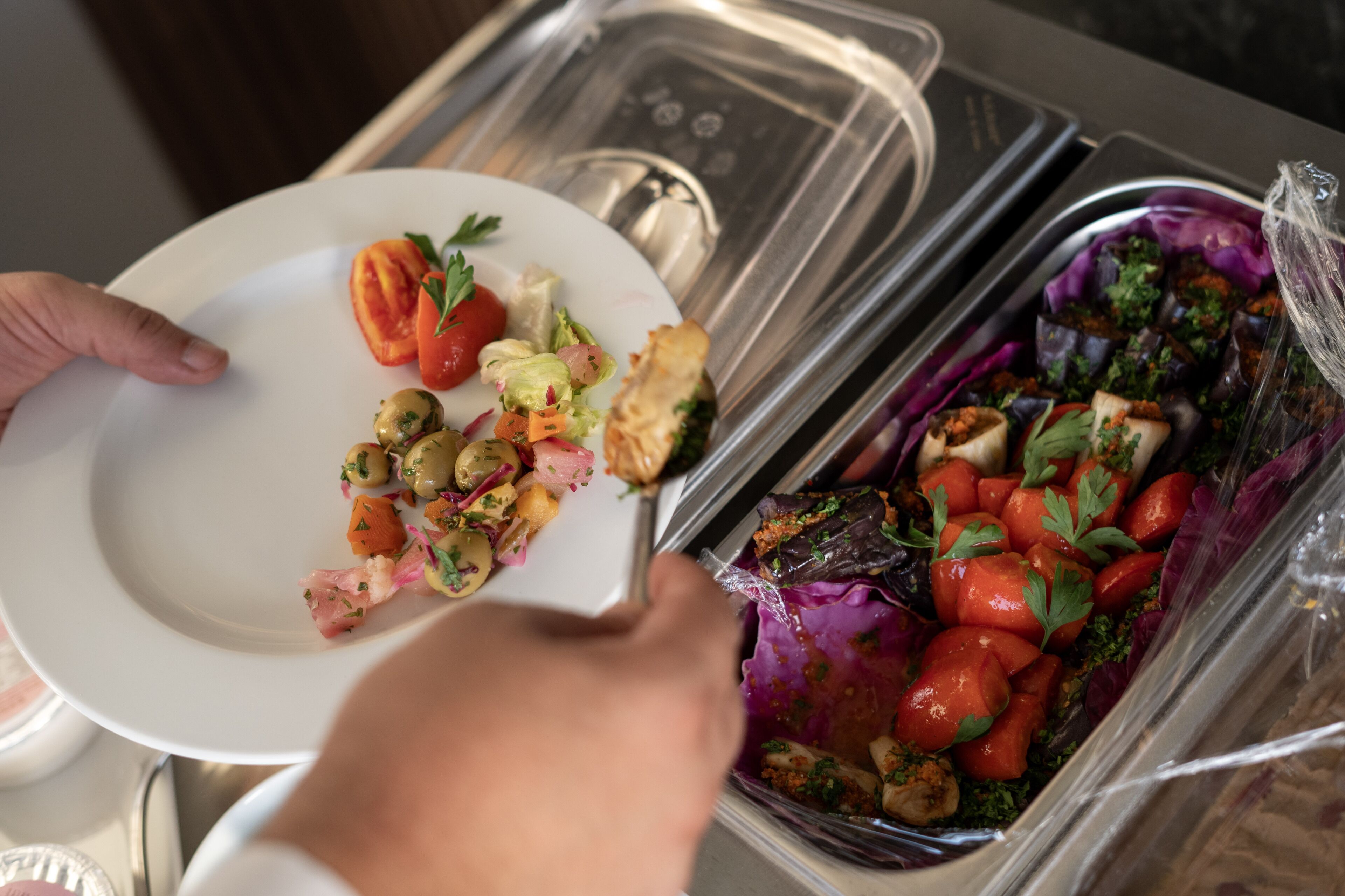 Disposição de buffet com diversos pratos, incluindo salada e um prato com carne e legumes.
