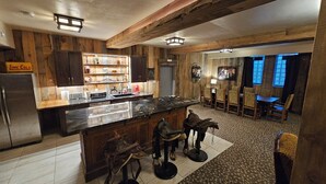 Uma cozinha rústica com armários de madeira, bancada de mármore e um espaço de bar com banquetas.