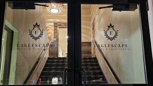 Uma escadaria leva a um edifício com portas de vidro e um logotipo com a inscrição "EAGLESCAPE SUITES & EVENT CENTER".