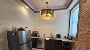 Cozinha moderna com eletrodomésticos de aço inoxidável, bancada de granito e luminária pendente.