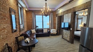 Uma sala de estar moderna com parede de tijolos, uma janela grande, um candelabro e um espaço de jantar com mesa e cadeiras.