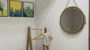 Quarto com estrutura de cama de madeira, um macramê pendurado, um espelho redondo e obras de arte na parede.