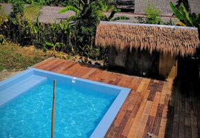 Uma piscina com deck de madeira e estrutura de telhado de palha.