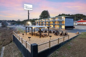 Um motel com área de estar coberta ao ar livre, mesas de piquenique e uma placa.