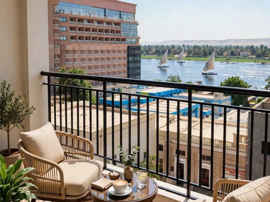 Varanda com mobiliário de vime, uma mesa pequena com xícara e pires, e vista para um rio com barcos.