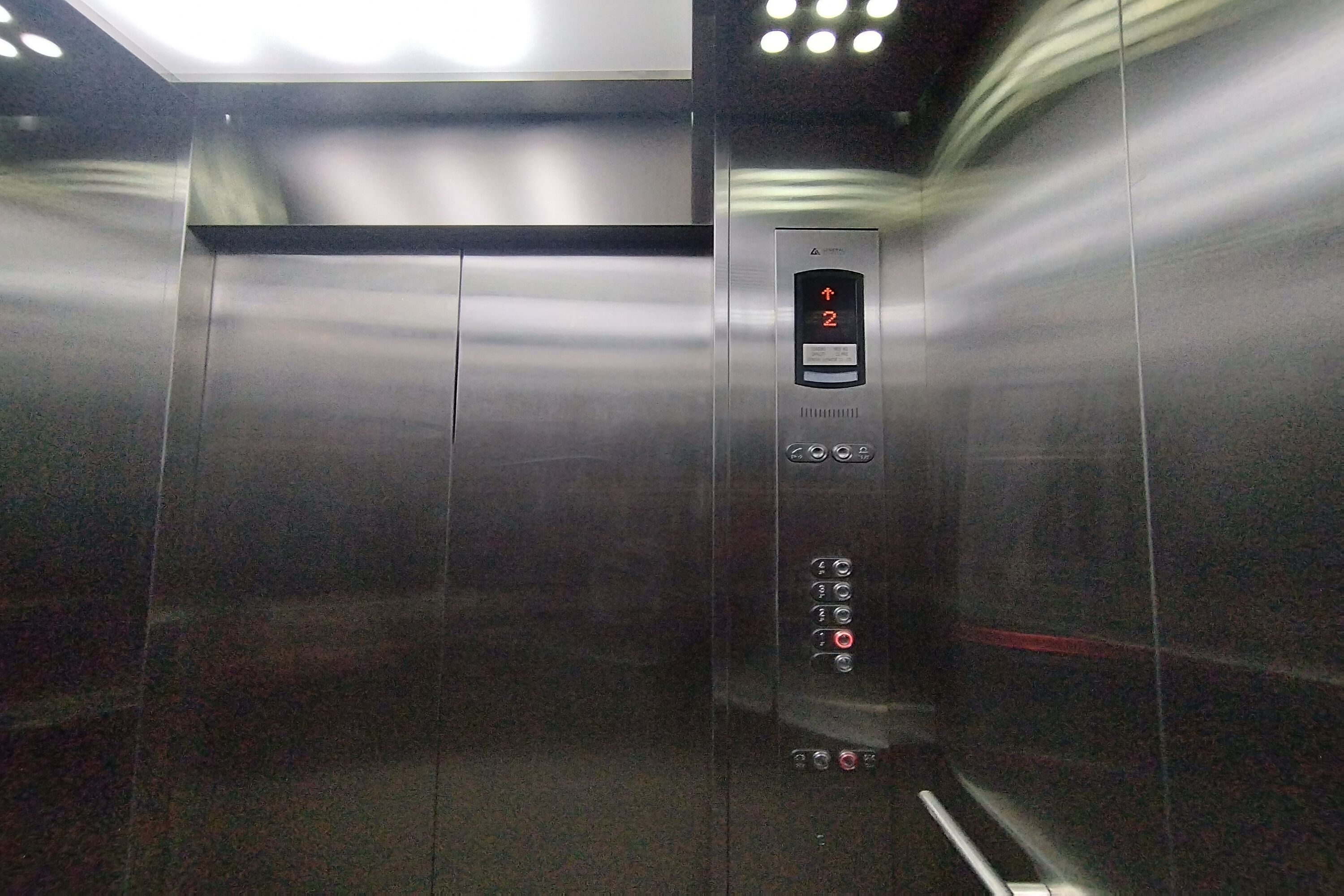 Interior de elevador com painel digital mostrando o número do andar e botões para selecionar os pisos.