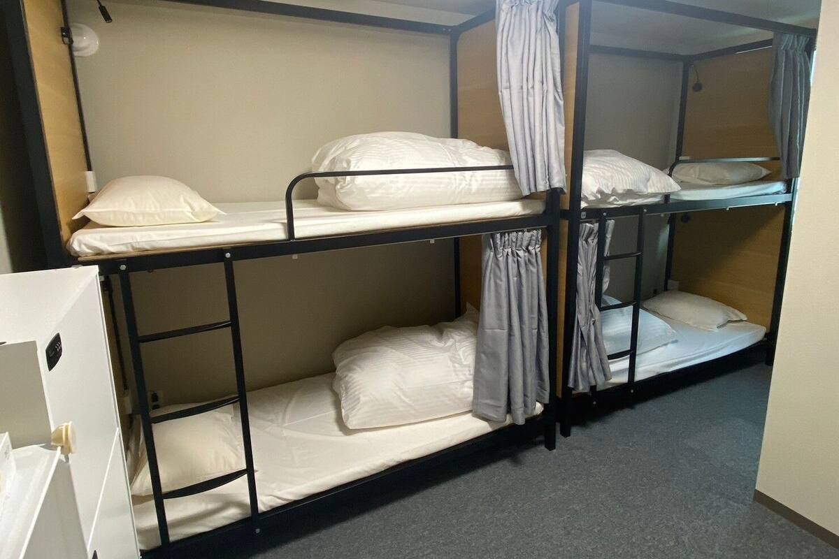 Quarto com beliche triplo, cada nível com colchão e almofadas.