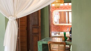 Quarto com cama, mesa de jantar com cadeiras, espelho e janela com cortinas.