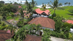 Uma vila costeira com casas tradicionais, vista clara do oceano e vegetação exuberante.