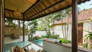 Uma área externa coberta com piscina, mobiliário e vegetação exuberante.