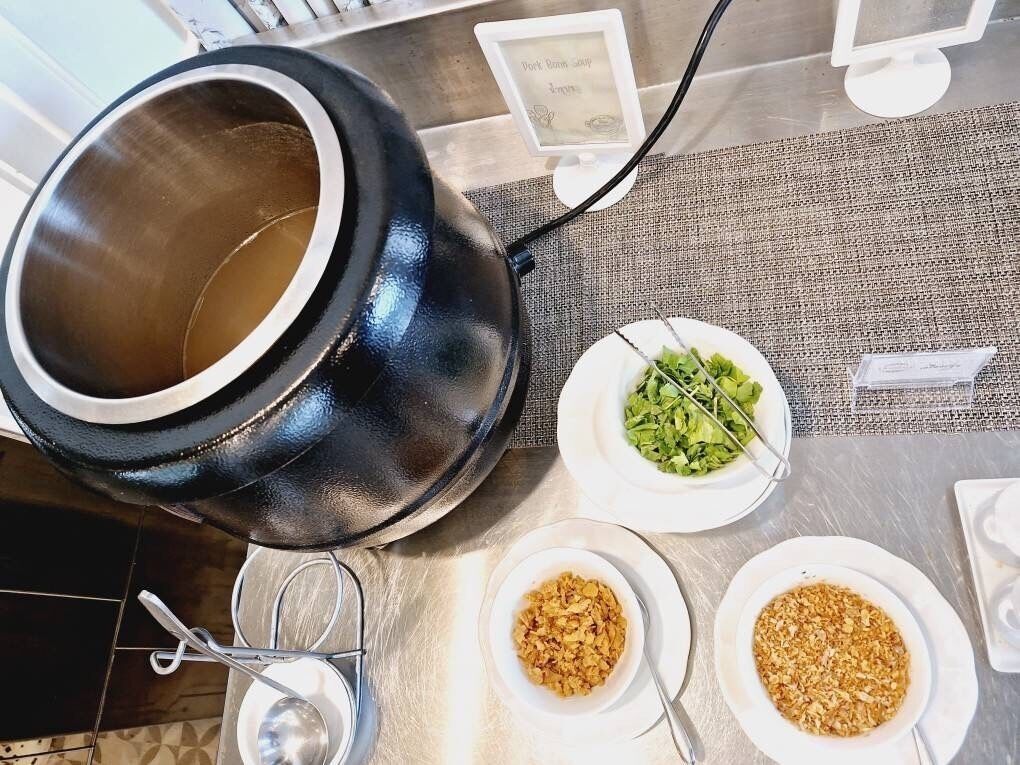 Uma área de cozinha com uma panela preta grande, dois recipientes com legumes picados e dois recipientes com granola.