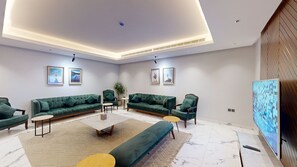 Uma sala de estar moderna com um sofá seccional, poltronas, uma mesa de centro e uma televisão de tela plana.