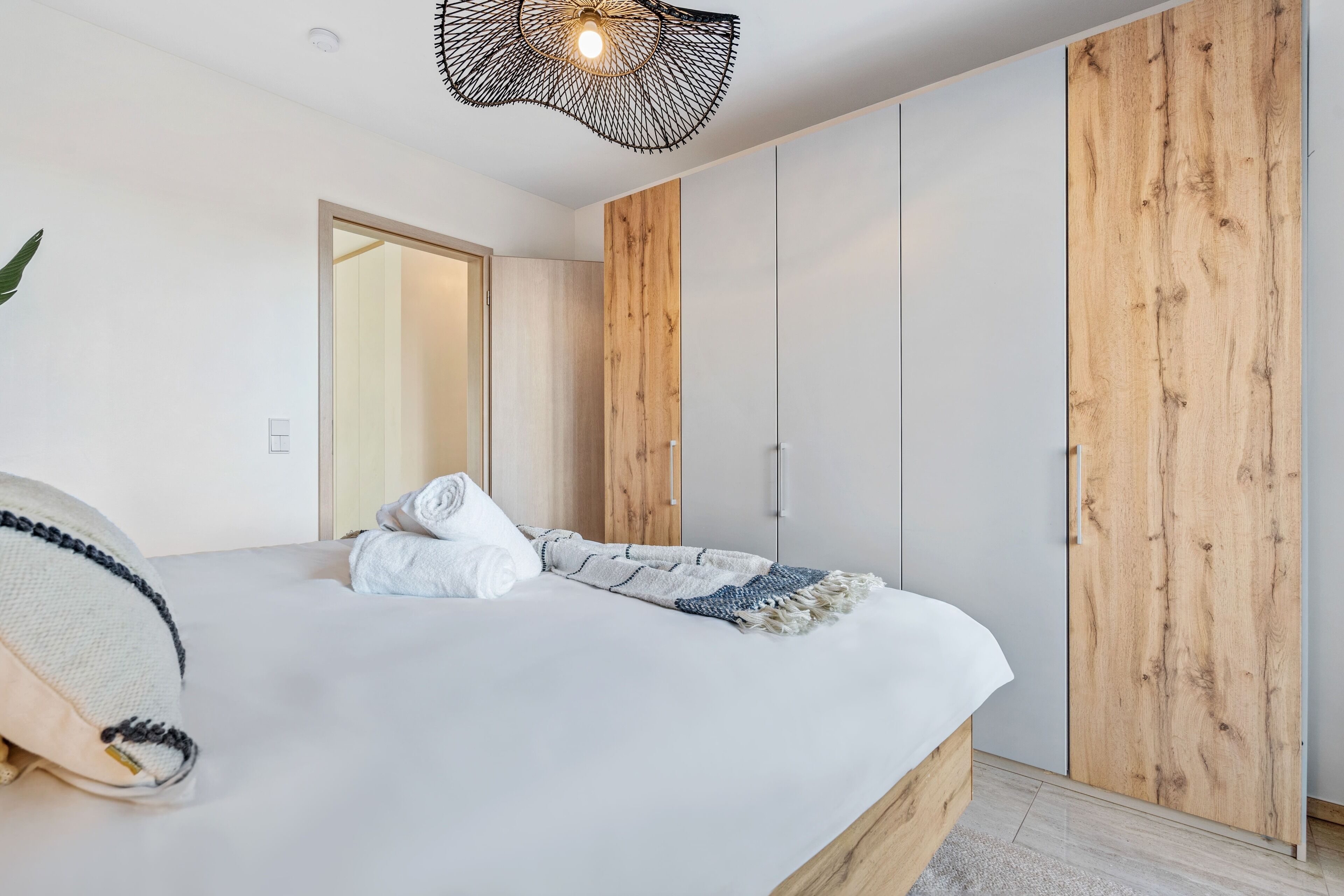 Quarto moderno com uma cama grande, guarda-roupa de madeira e uma luminária pendente original.