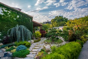 Um jardim com um caminho de pedra, diversas plantas e um banco.