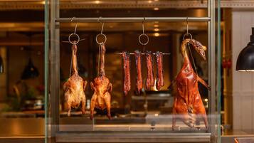 Diversos tipos de carne pendurados em uma vitrine, provavelmente em um restaurante ou empório.