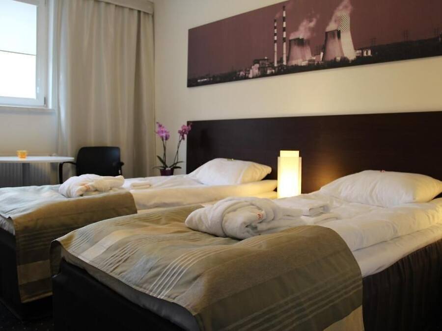 Quarto de hotel com duas camas, uma mesa e uma janela.