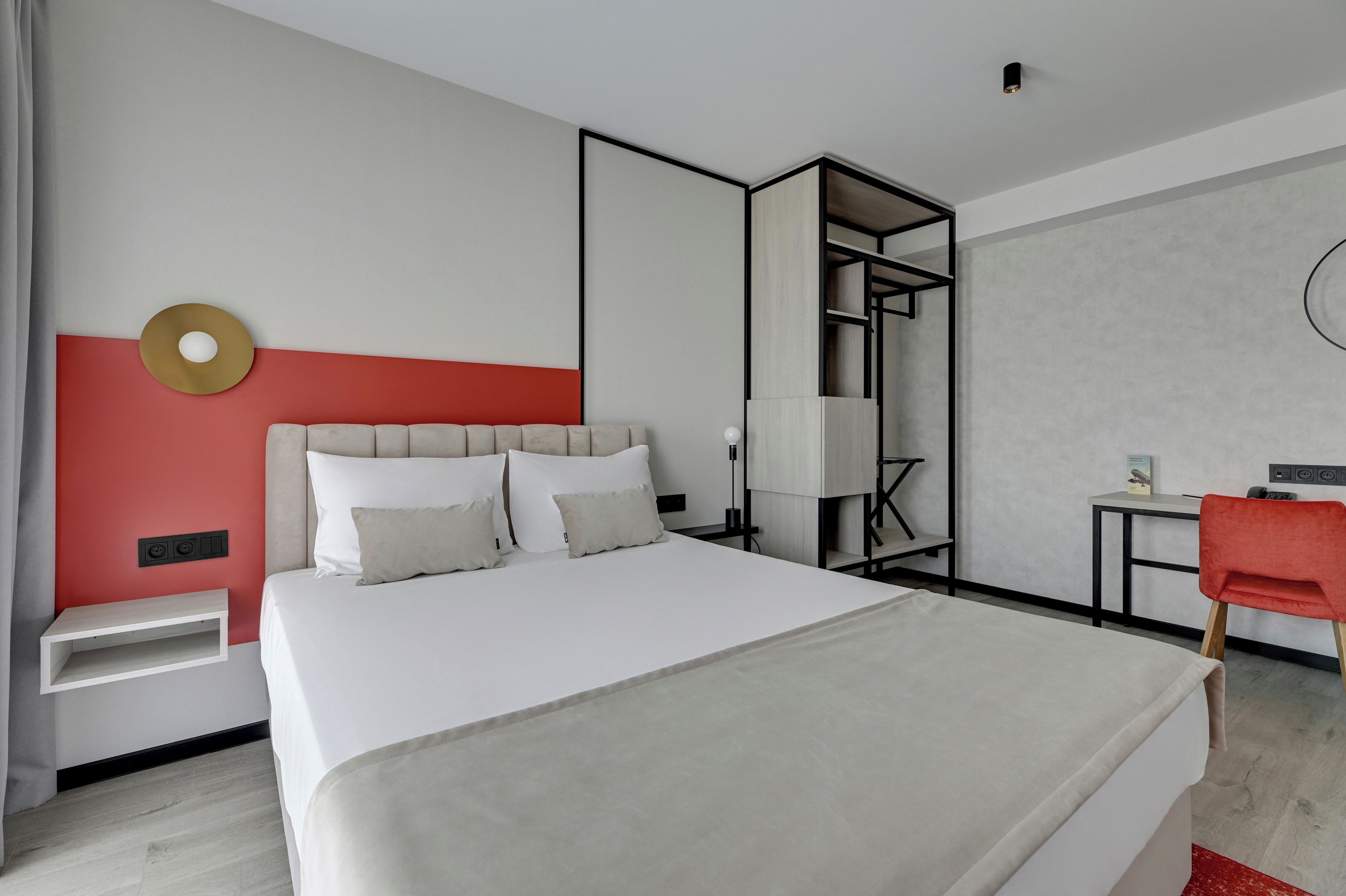 Quarto de hotel com uma cama grande, uma escrivaninha, uma cadeira e um guarda-roupa.