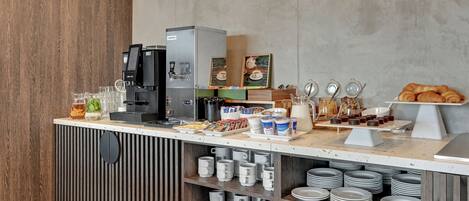 Um buffet de café da manhã com máquinas de café, diversas opções de alimentos e uma seleção de doces.