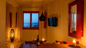Uma sala de jantar com mesa, cadeiras, garrafa de vinho e uma vela.