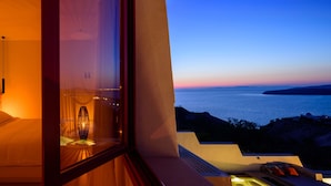 Quarto com vista para o mar ao entardecer.