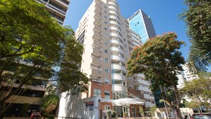 Um hotel com vários andares, fachada curva, entrada central e área de estacionamento.