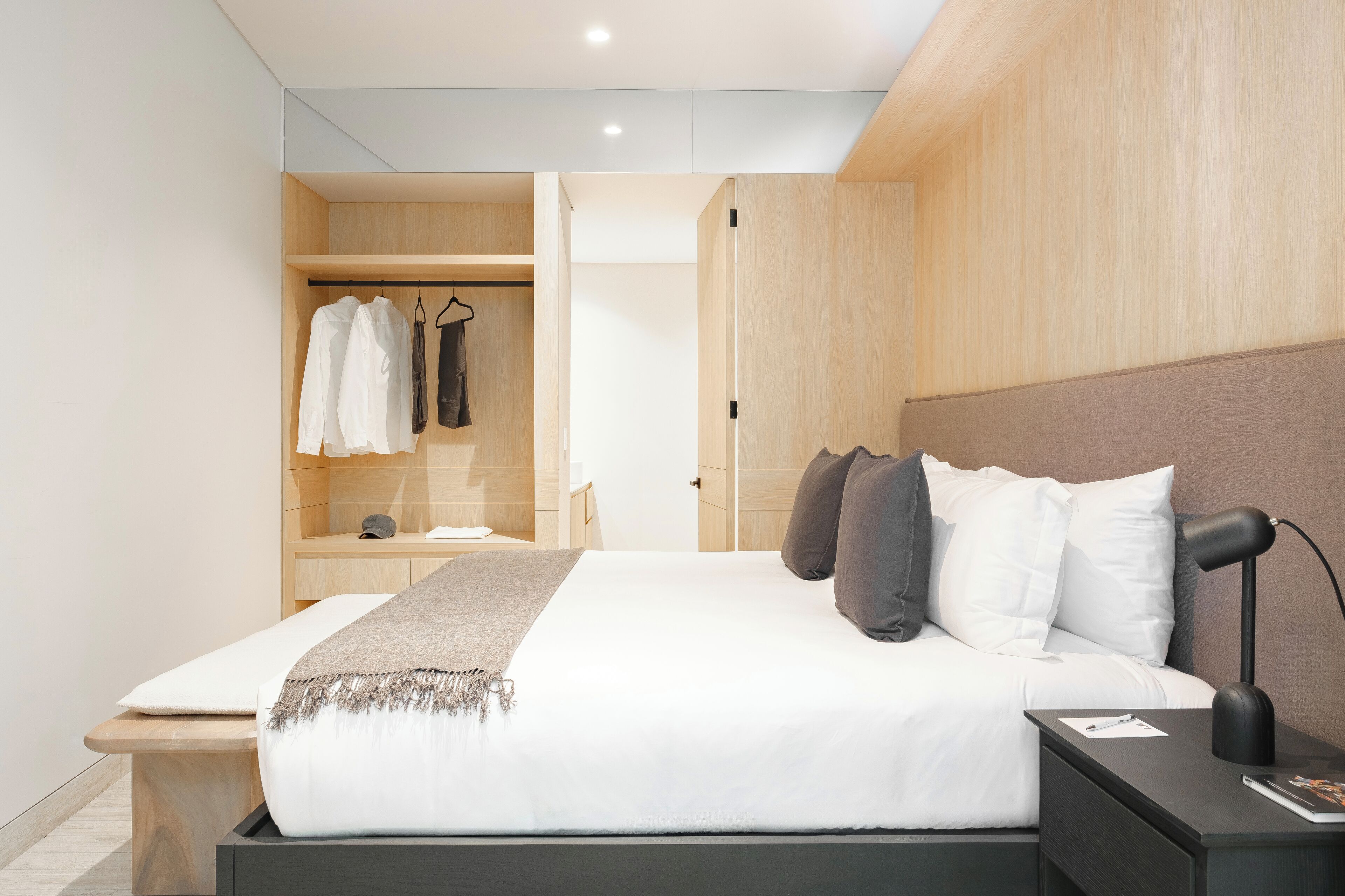Quarto bem arrumado com cama, mesa de cabeceira e guarda-roupa.