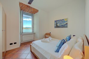 Quarto com cama, janela com vista, quadro na parede e radiador.