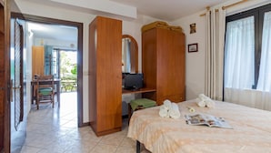 Quarto de hotel com cama, televisão, secretária e uma cadeira.