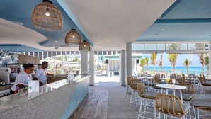 Uma área de bar moderna, com balcão, banquetas e luminárias de vime suspensas.