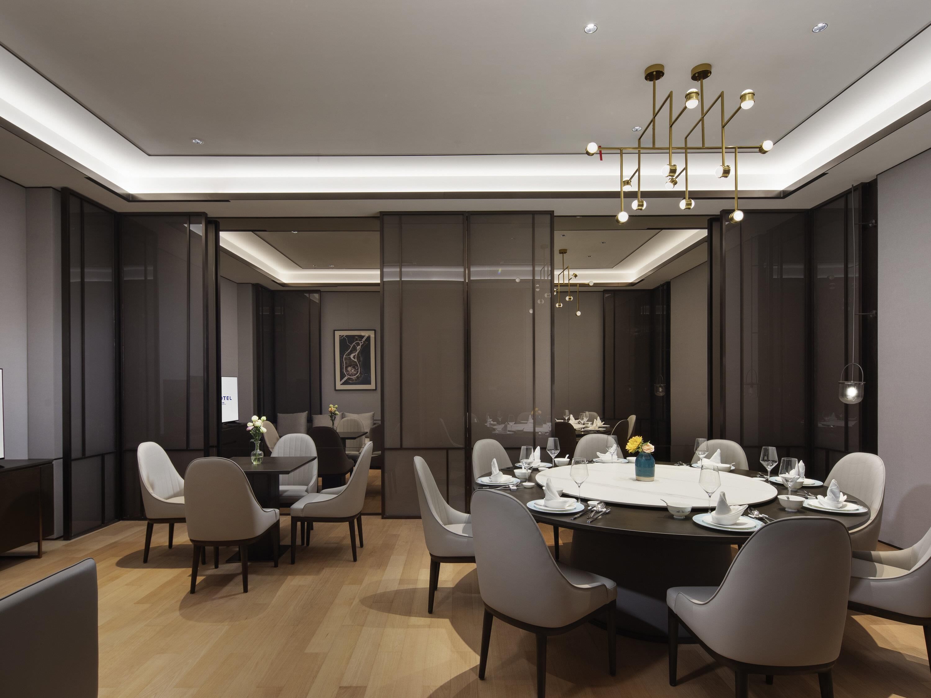 Uma sala de jantar moderna com uma mesa redonda posta para seis pessoas, rodeada por seis cadeiras.